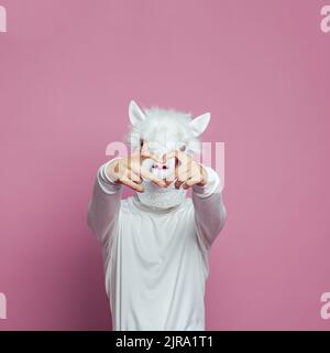 Cute lama person. Man with lama head saying hello on bright pink studio ...