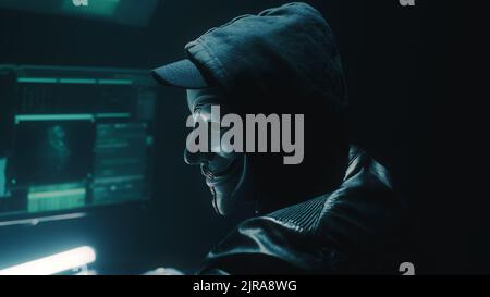 A masked hacker weared black hoodie uses a computer to stage a massive ...