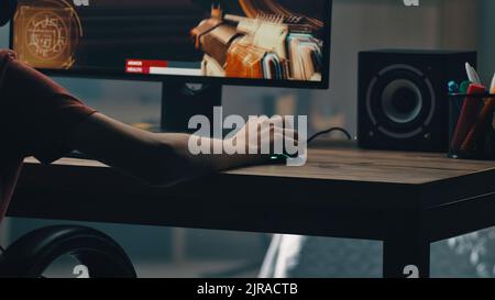 Unrecognizable teenager using computer mouse to aim weapon while ...