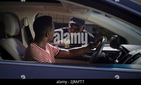 African American police officer checking driver license of black man in ...