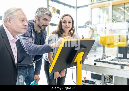 Technicians in industrail factory explaining control panel to senior ...