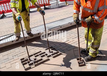 Workers using forming tools on asphalt to create the impression of ...