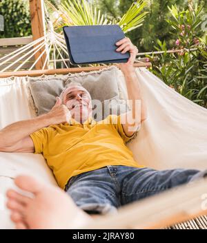 Senior man gesturing on video call having through smart phone sitting ...