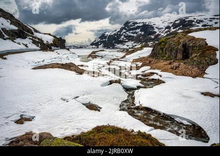 Norway, Rogaland, Sauda, Road 520 stretching between snow-covered hills ...