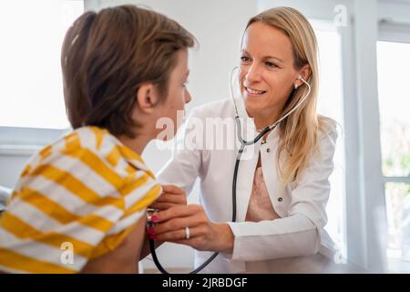 Female doctor with stethoscope examining boy Stock Photo - Alamy