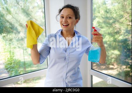 Pretty housewife smiling cutely at camera, holding a mold with rolled ...