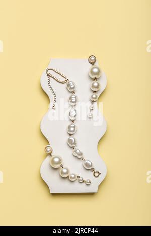 Showcase pedestal with pearl jewelry on color background Stock Photo ...