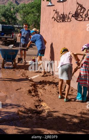Volunteers shovel mud from the front of a local business the day after ...