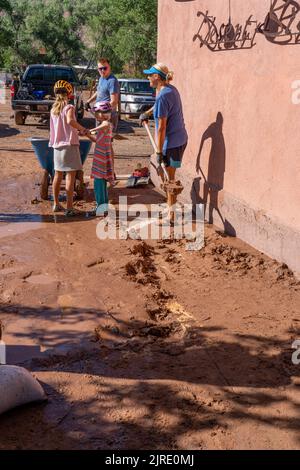 Volunteers shovel mud from the front of a local business the day after ...