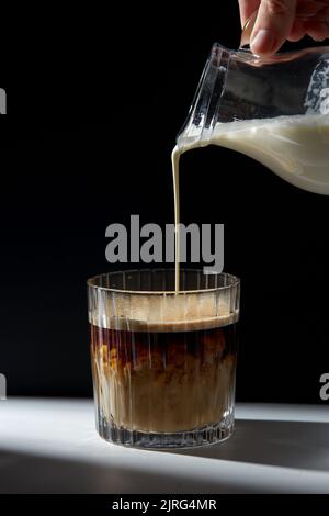 hand with jug pouring cream to glass of coffee Stock Photo - Alamy