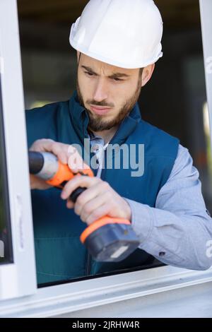 male fitter using cordless power-tool on window frame Stock Photo - Alamy