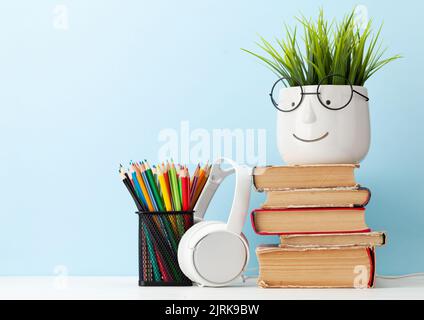 Old books, supplies and headphones on wooden table and blackboard for ...