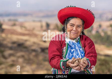 Senior Peruvian female farmer in traditional costume standing in rural ...