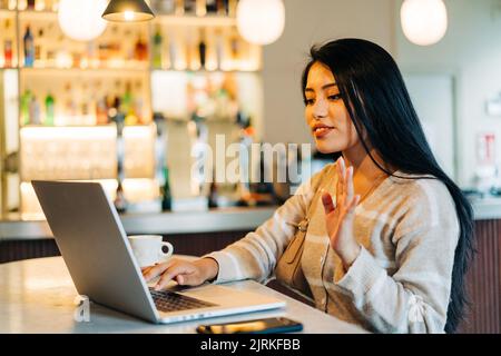 Asian woman waving hand during video call on tablet at home Stock Photo ...