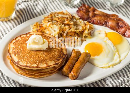Full American Breakfast with Bacon, Hash Browns, Eggs and Pancakes on a plate on a white wooden ...