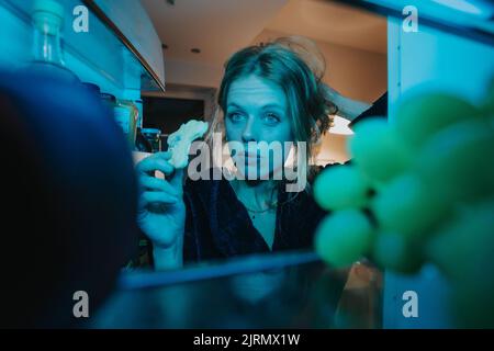 A female looking inside the open fridge at night Stock Photo - Alamy