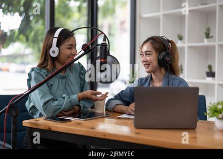 two asian radio podcasters recording interview each other for radio ...