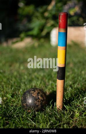 Outdoor croquet game set with pole, wickets and red ball in grassy park ...