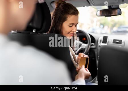 female car driver takes credit card from passenger Stock Photo - Alamy
