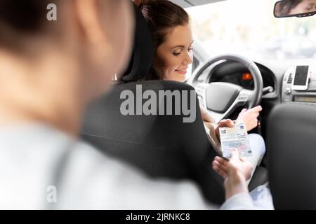 female car driver taking money from passenger Stock Photo - Alamy