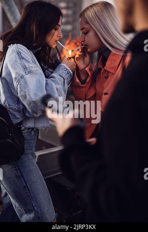 Two rebellious teenage girls lightning cigarettes and smoke. Teenagers ...