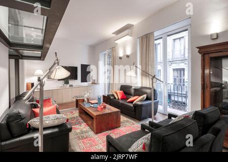 Living room with balconies facing the street, long sofa upholstered in ...