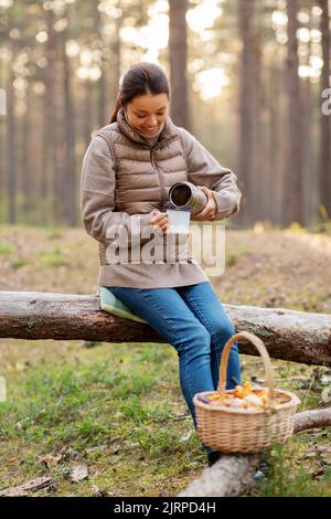 Young woman with thermos drinking hot tea in forest, closeup Stock ...