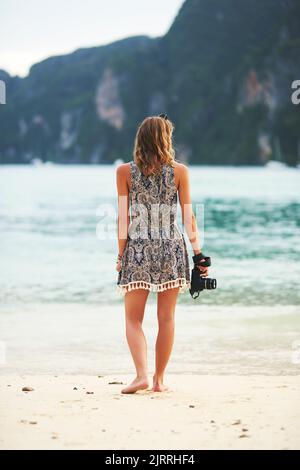Rear view shot of a relaxed woman walking along a beach Stock Photo - Alamy