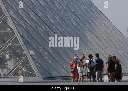 Tourists enjoys near Pyramid at the Louvre Museum during a hot summer ...
