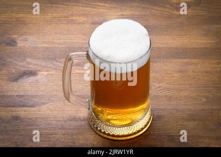 A large mug of light tasty cold beer on a wooden table, close-up ...
