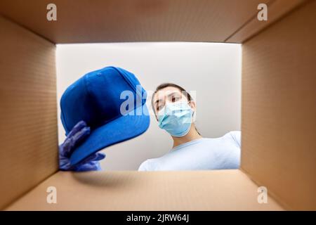 woman in mask opening parcel box with photo frame Stock Photo - Alamy