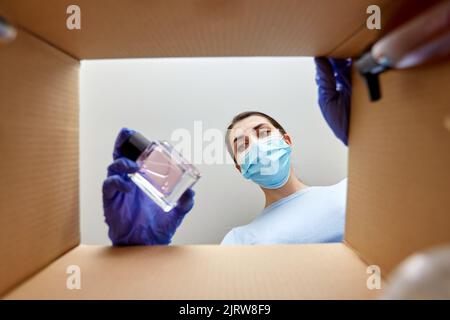 woman in mask unpacking parcel box with cosmetics Stock Photo - Alamy