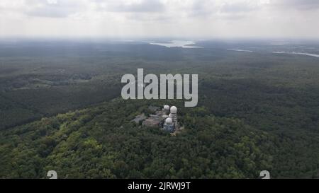 An aerial view of Teufelsberg surrounded by lush trees with a cloudless ...