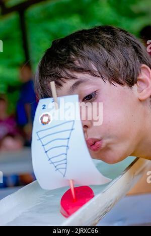 A Cub Scout urges his wind-driven sailboat to the finish line during ...