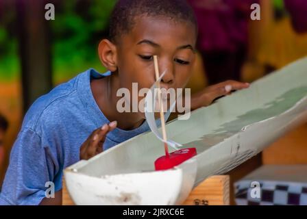 A Cub Scout urges his wind-driven sailboat to the finish line during ...