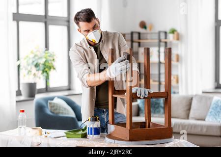 man in respirator sanding old table with sponge Stock Photo - Alamy