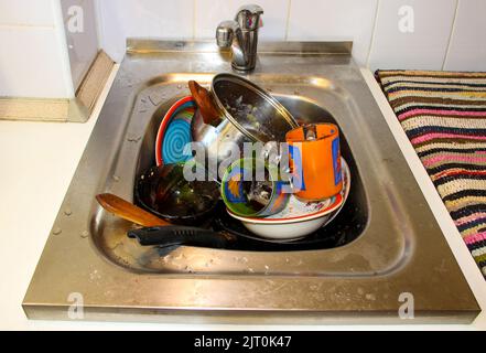 mass of dirty dishes with food scraps waiting to be washed in the metal ...