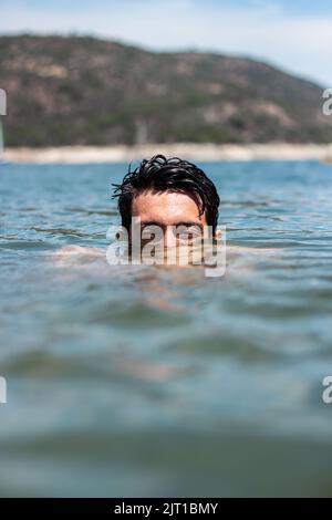 Handsome Caucasian man submerged in water. He is on a beach and his ...