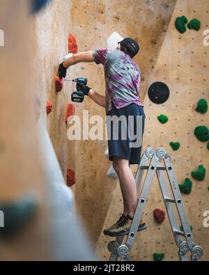 A climbing route setter trying to set a route in the bouldering gym ...