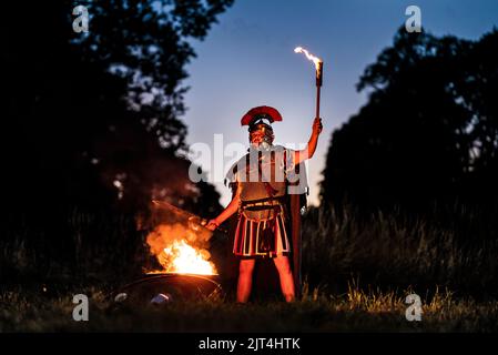 Roman living history reenactor holds a flaming torch next to a fire ...