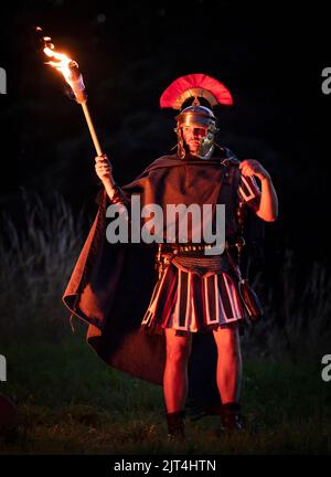Roman living history reenactor holds a flaming torch next to a fire ...