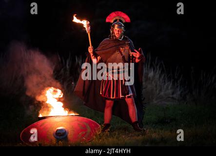 Roman living history reenactor holds a flaming torch next to a fire ...