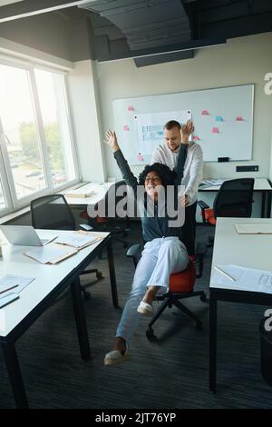 Crazy, chair and colleagues in office, ride and celebration for work ...