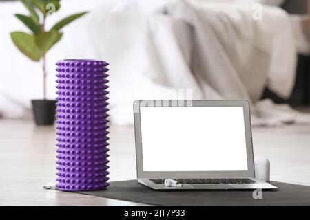 Foam roller and laptop on mat in room Stock Photo - Alamy