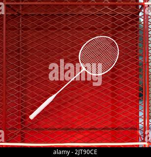 one badminton racket is hung on red grill by a cable tie for display in ...
