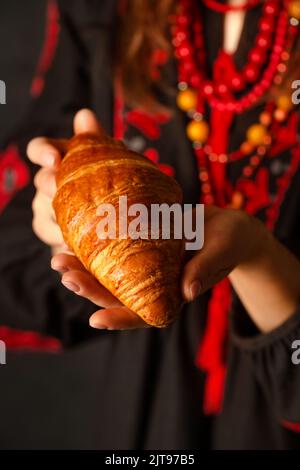 Crispy fresh red croissant with cream and strawberries on a dark ...