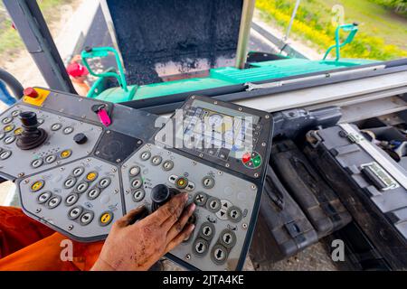 Worker, operator is controlling tarmac road laying machine with ...