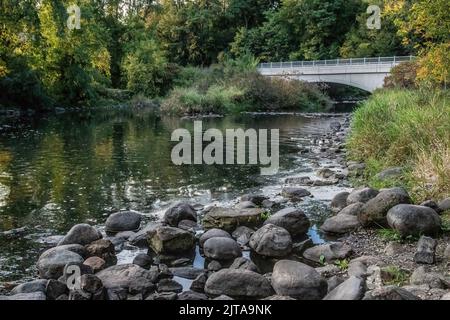 A beautiful serene river surrounded with stones in a park with colorful ...