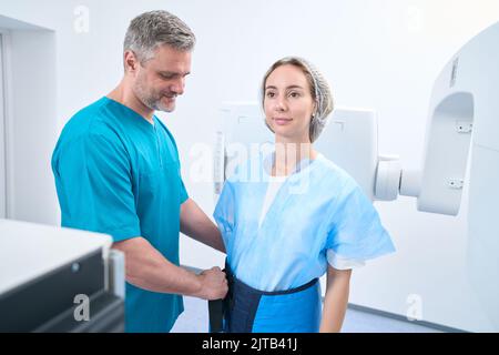 Radiologist at medical center putting lead shield on female patient ...