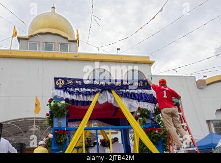 A Sikh man puts bunting on the mani float of the 2022 Nagar Kirtan ...
